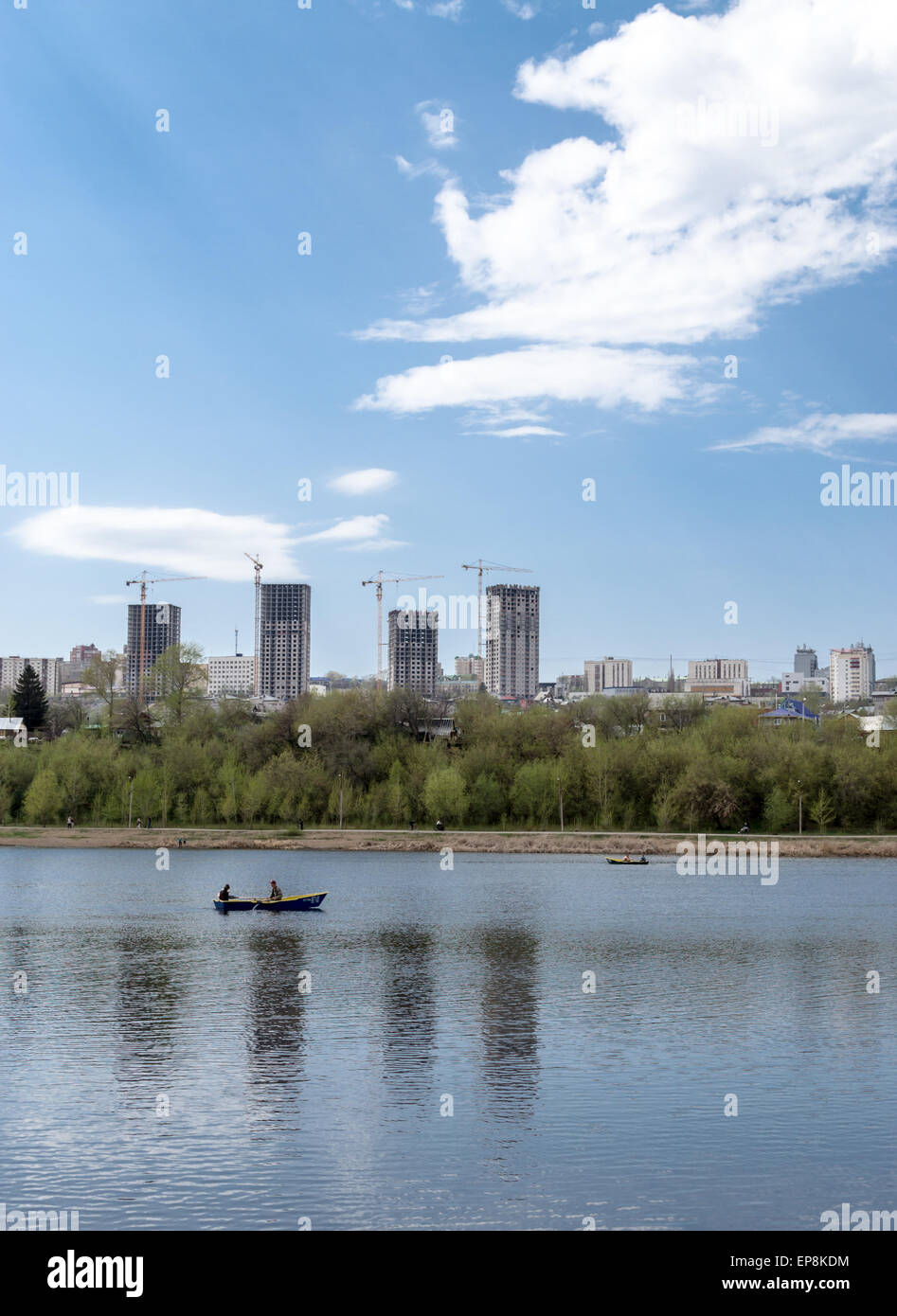 Single rowing boat on a lake with high-rise apartments Stock Photo - Alamy