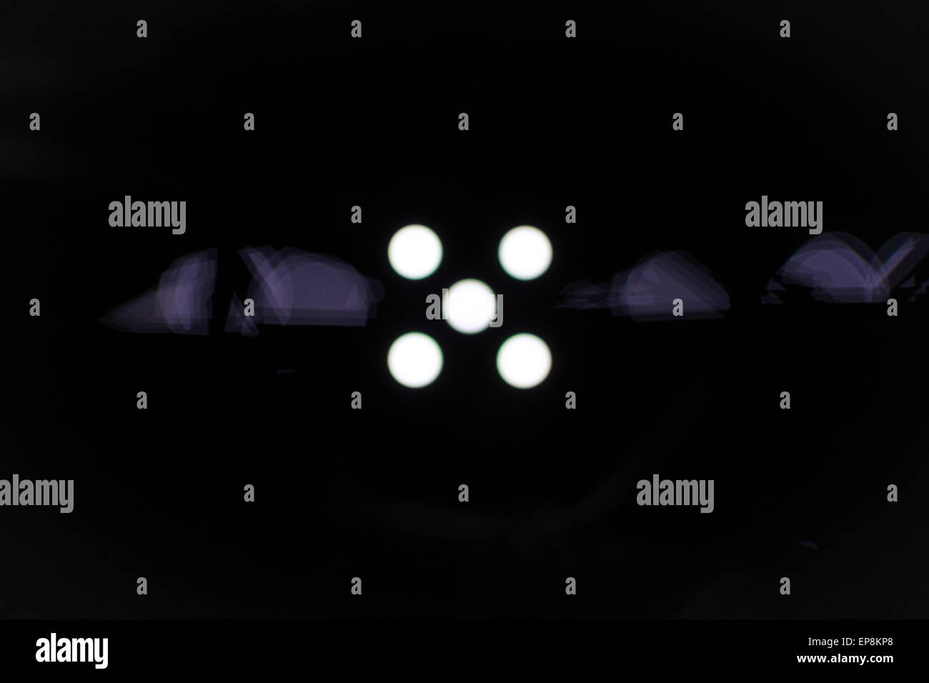 Five white dots on a black background with light defraction in a ...