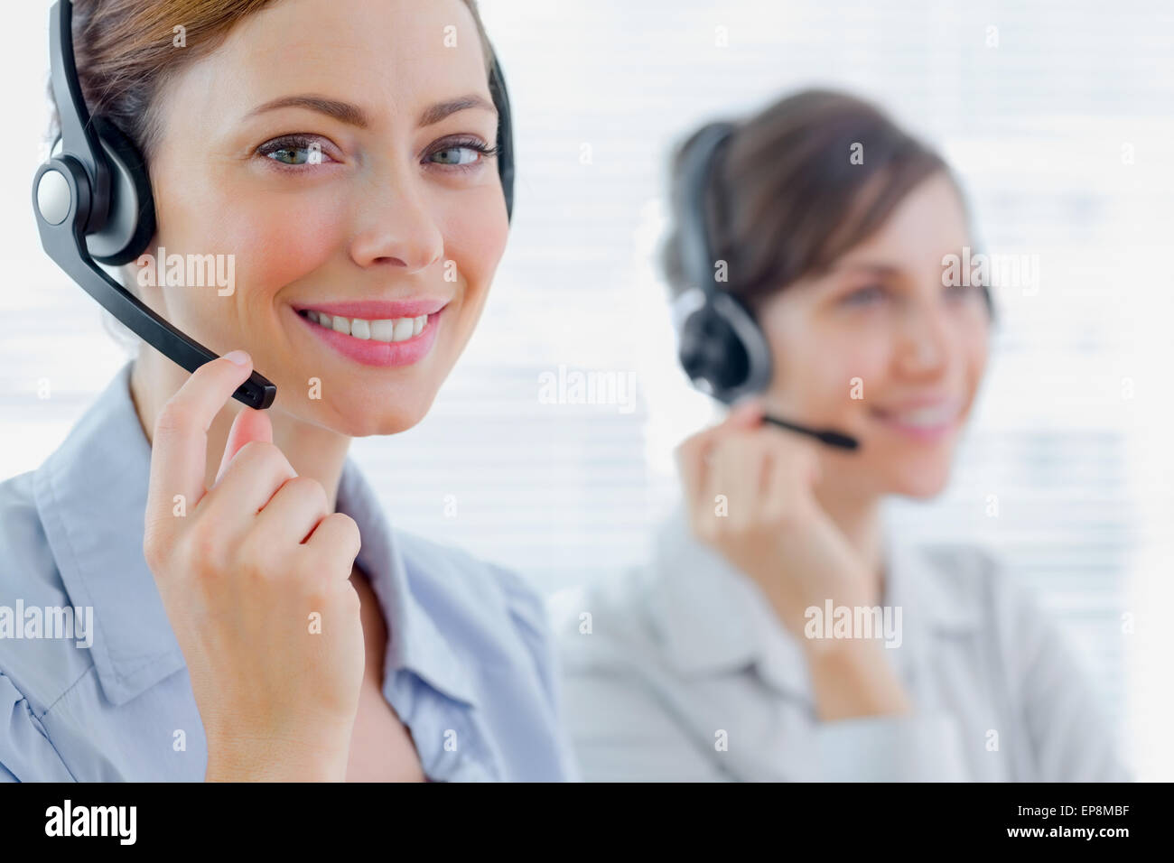 Smiling call centre agents with headsets at work Stock Photo - Alamy