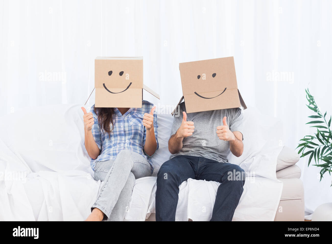 Couple sitting with cardboard boxes on head giving thumbs up Stock ...