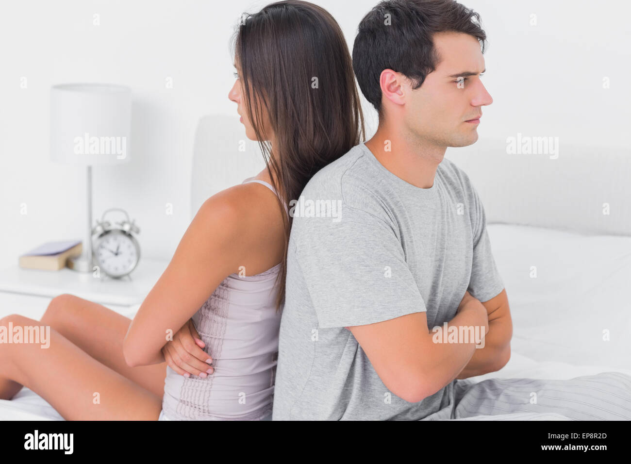 Couple sulking each other sitting back to back on bed Stock Photo - Alamy