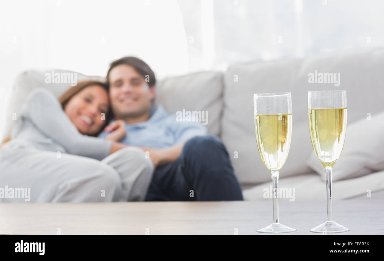Couple resting on a couch with flutes of champagne Stock Photo - Alamy