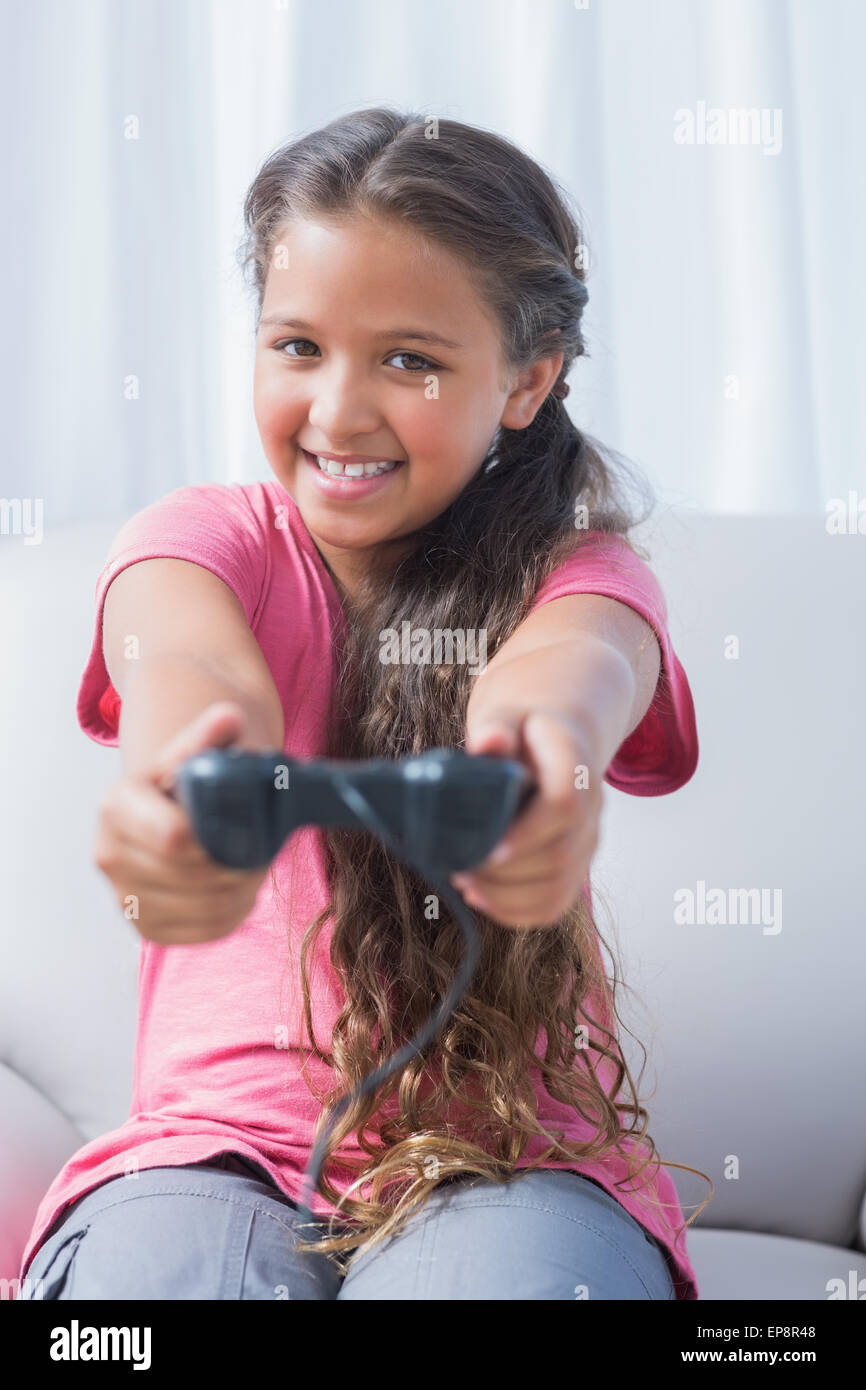 Smiling little girl playing video game on sofa Stock Photo - Alamy