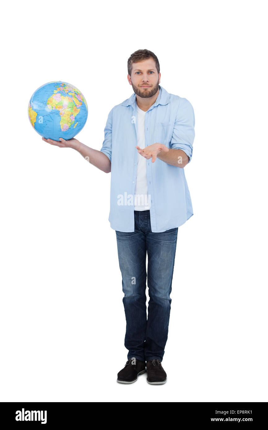 Charming model holding a globe and shrugging shoulders Stock Photo - Alamy