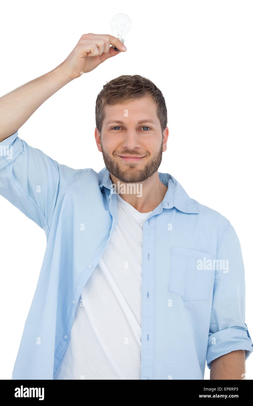 Sceptical model holding a bulb above his head and looking at camera ...