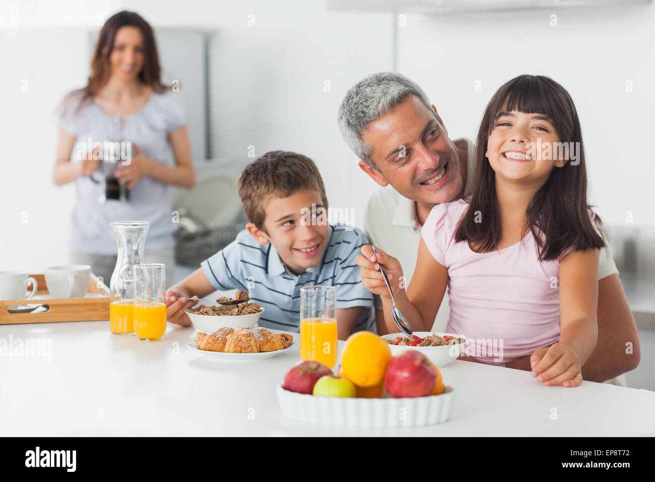 Smiling family eating breakfast in kitchen together Stock Photo - Alamy
