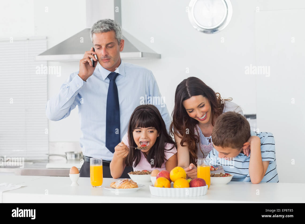 Father calling with mobile phone with his family eating breakfast Stock ...