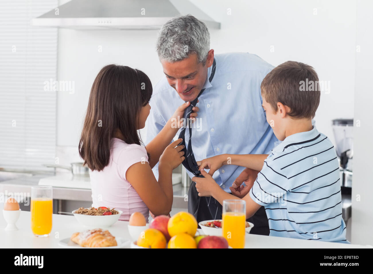 Children fixing their fathers tie in the kitchen Stock Photo - Alamy
