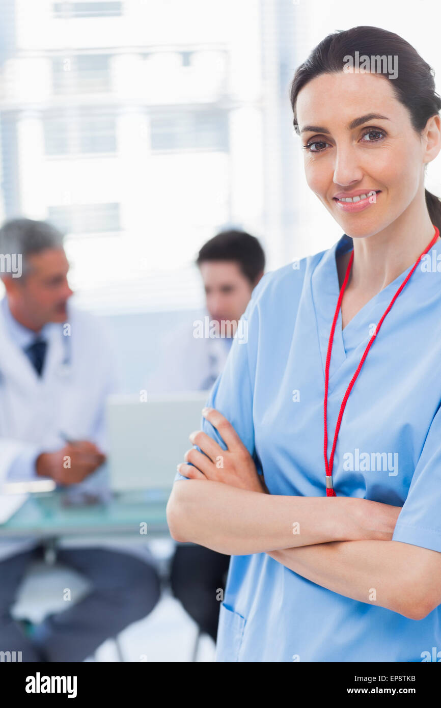 Nurse crossing arms with her colleagues behind Stock Photo - Alamy