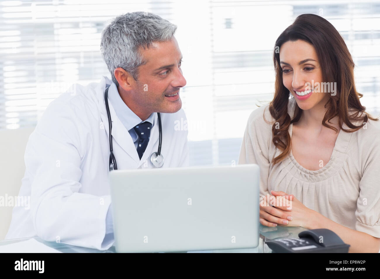 Docter showing something on laptop to his patient Stock Photo - Alamy