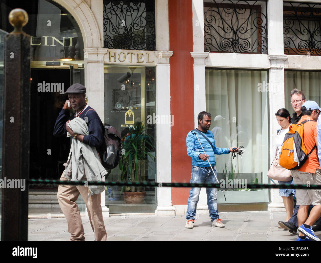 A modern day Merchant of Venice, a street vendor,selling "selfie sticks ...
