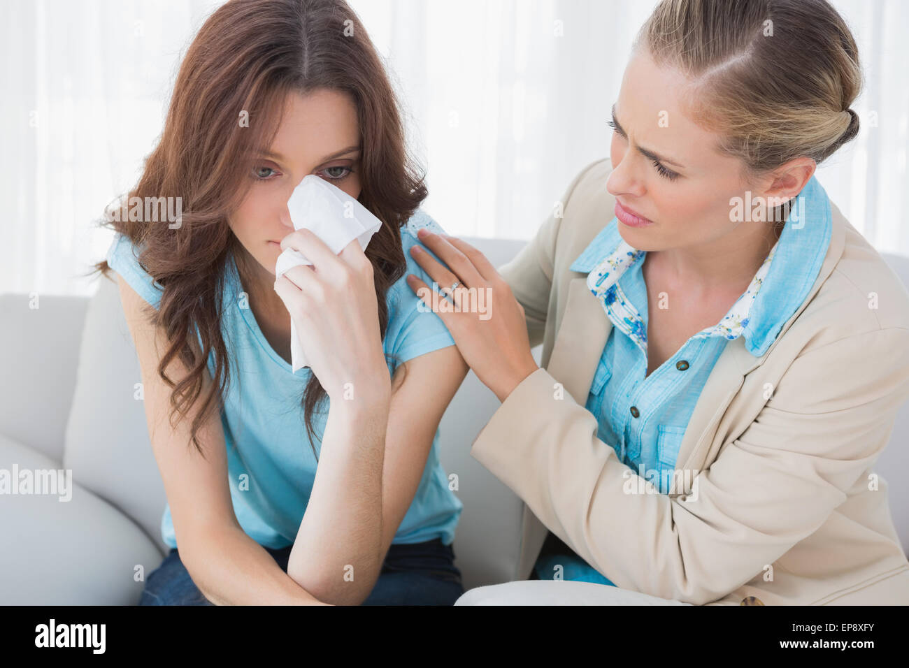 Blond therapist looking at her patient crying Stock Photo - Alamy