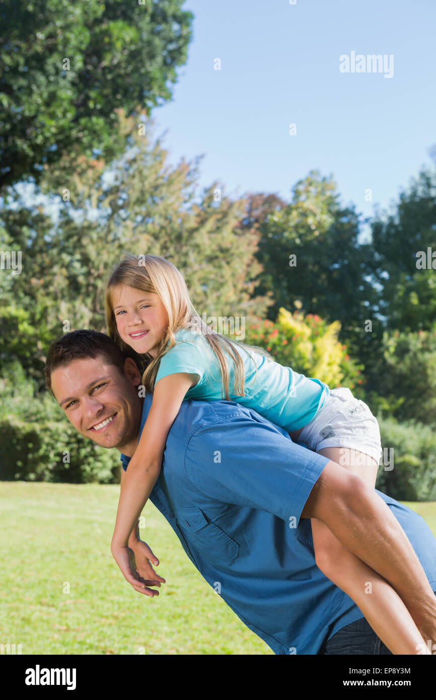 Daughter getting piggy back from dad smiling at camera Stock Photo - Alamy
