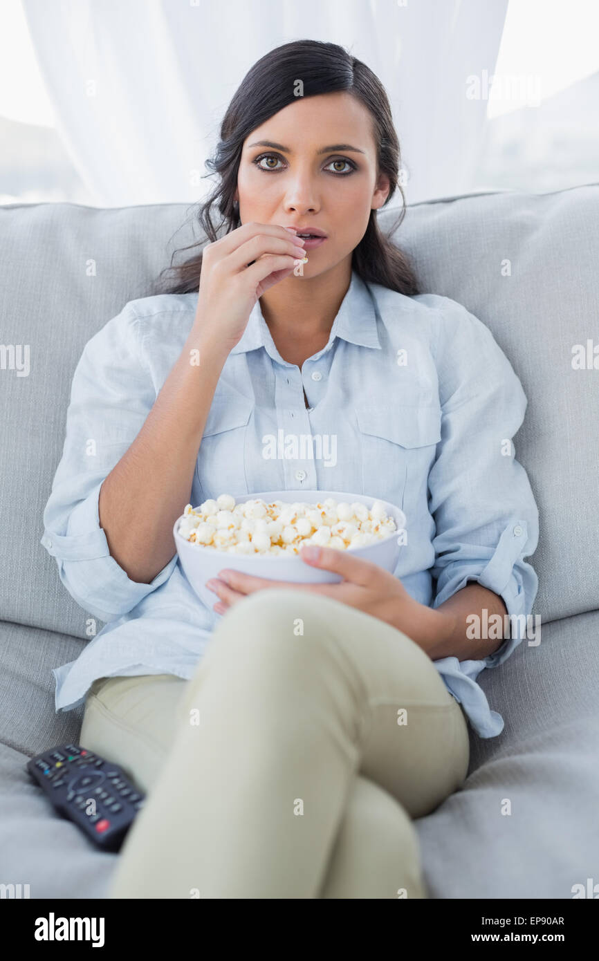 Concentrated pretty brunette watching tv and eating pop corn Stock ...