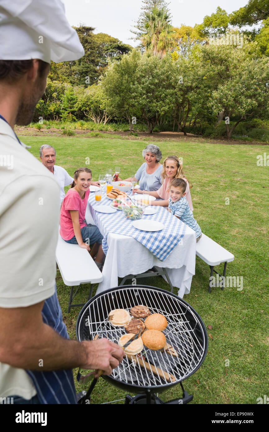 Happy extended family having a barbecue being cooked by father in chefs ...