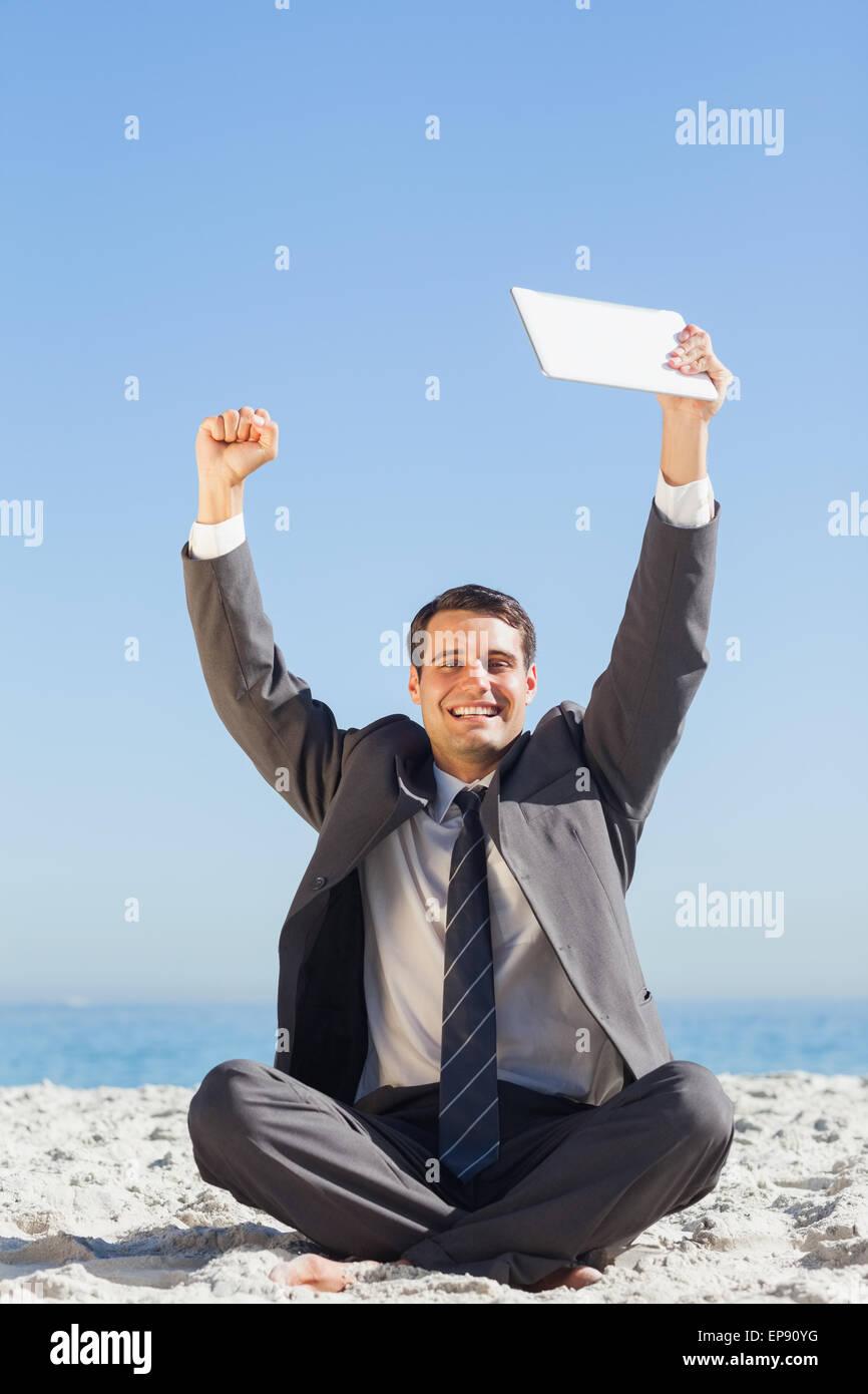 Victorious young businessman holding up his tablet computer Stock Photo ...