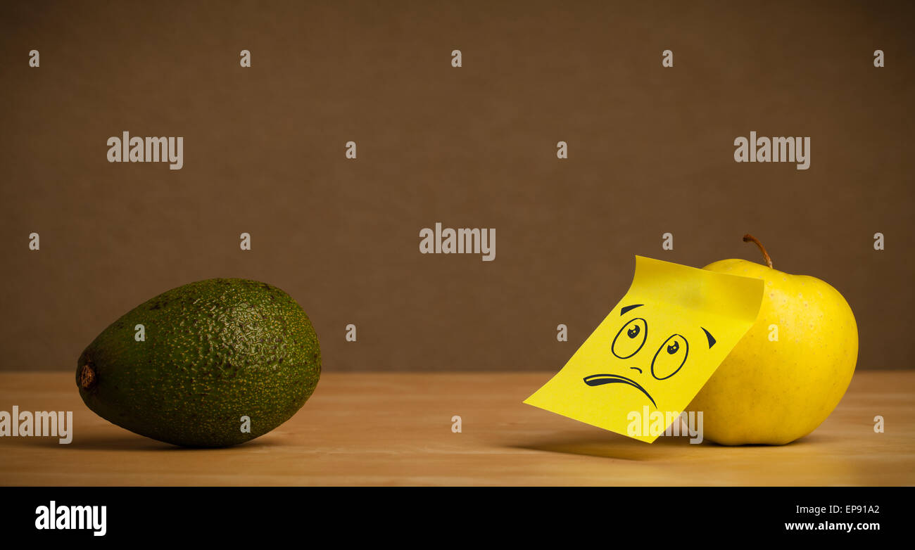 Apple with sticky post-it note looking sadly at avocado Stock Photo - Alamy