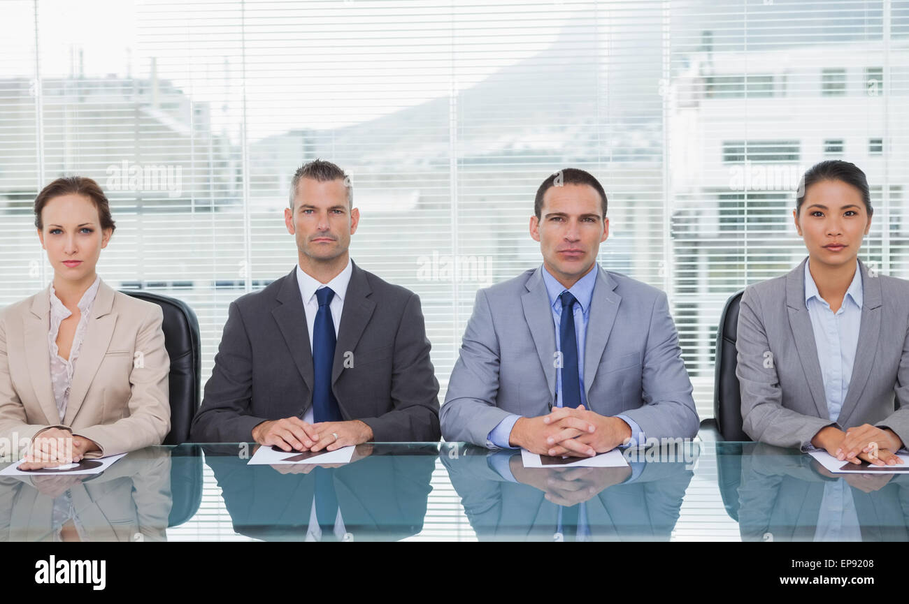 Stern business people sitting straight looking at camera Stock Photo ...