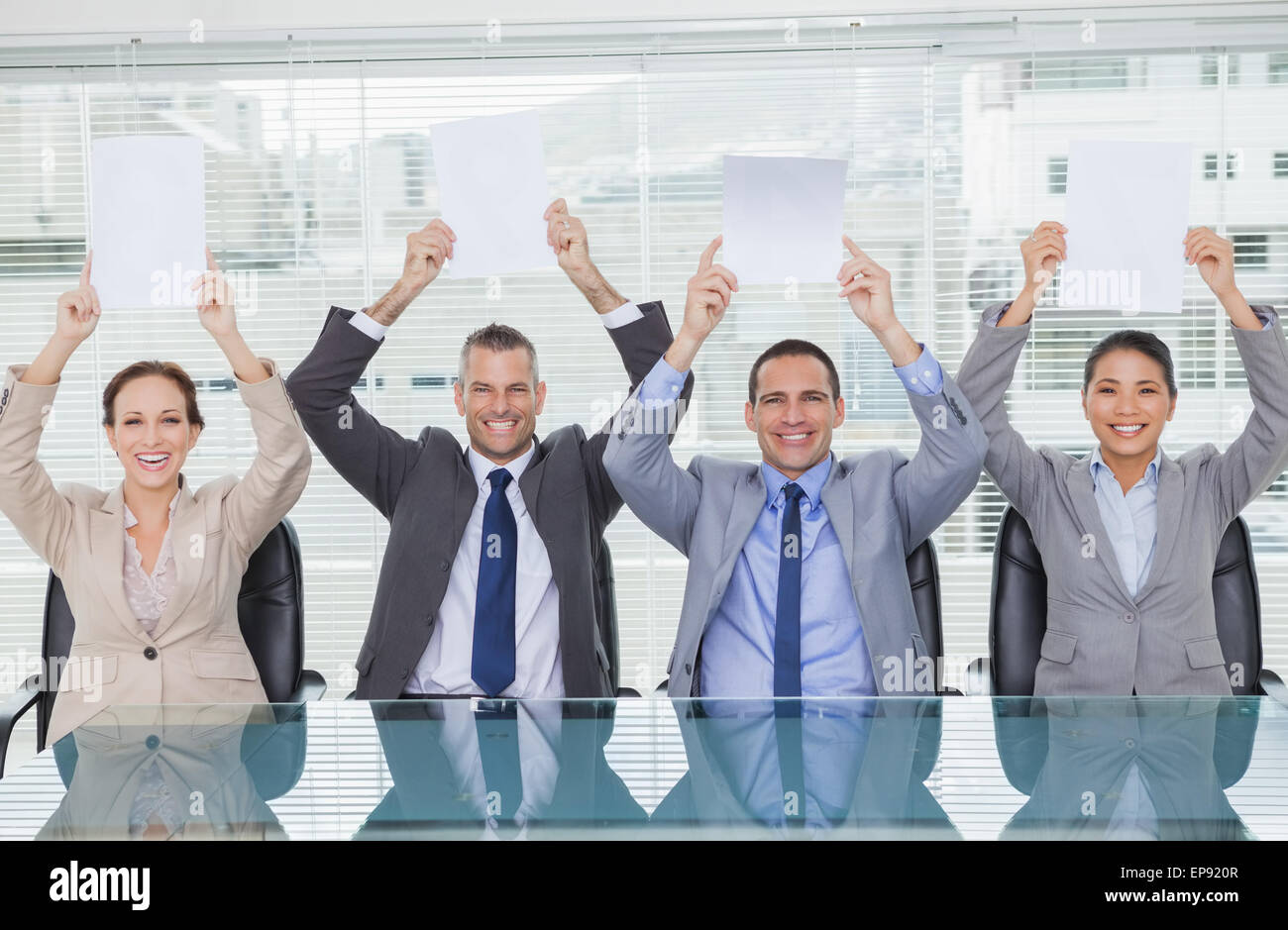 Smiling interview panel holding blank sheets above their head hiding ...