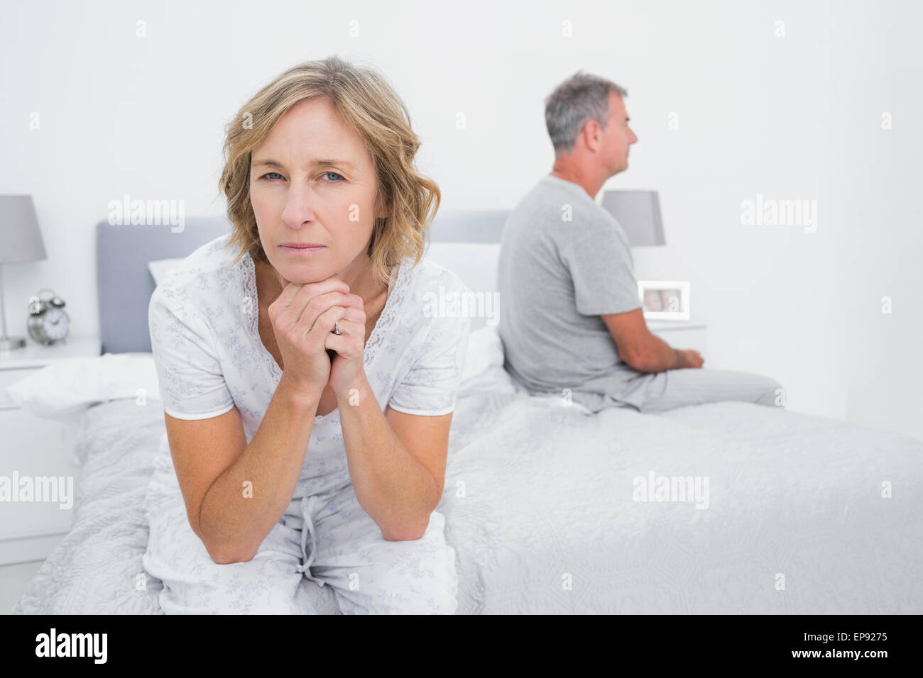 Thoughtful Couple Sitting On Different Sides Of Bed Having A Dispute