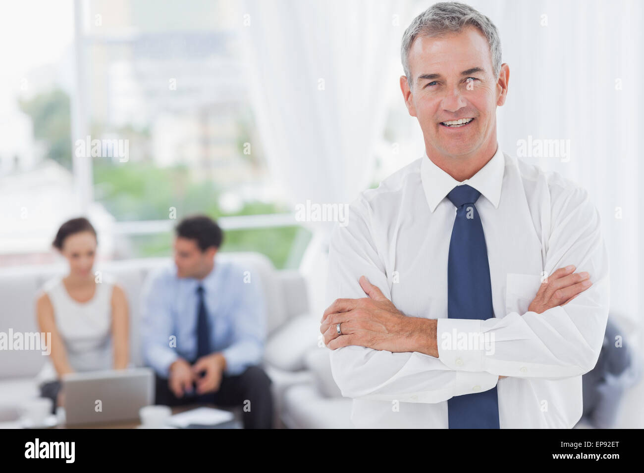 Executive posing while his colleagues are working Stock Photo - Alamy