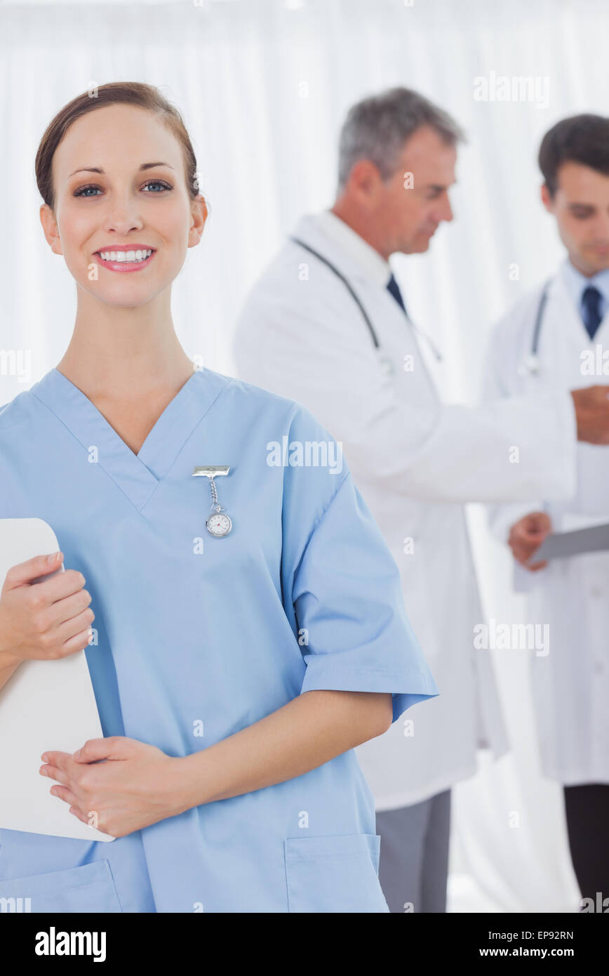 Cheerful surgeon posing while doctors talking on background Stock Photo ...