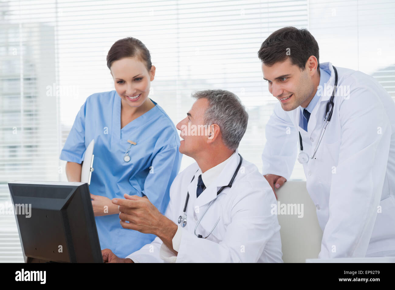 Cheerful doctors and surgeon working together on computer Stock Photo ...