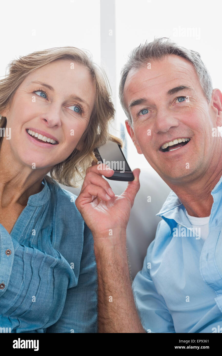 Smiling couple listening to mobile phone together Stock Photo - Alamy