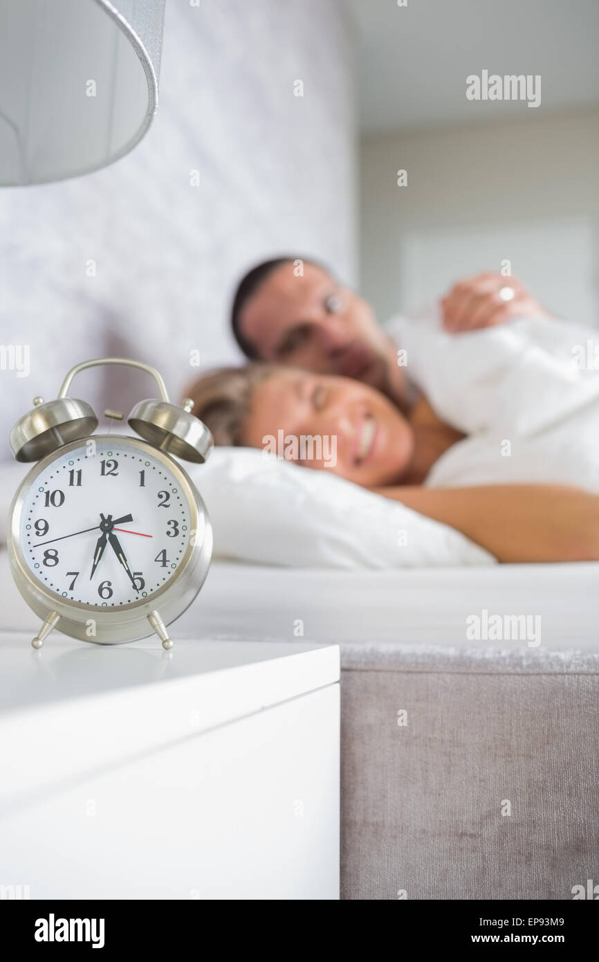 Tired couple looking at alarm clock in the morning Stock Photo - Alamy