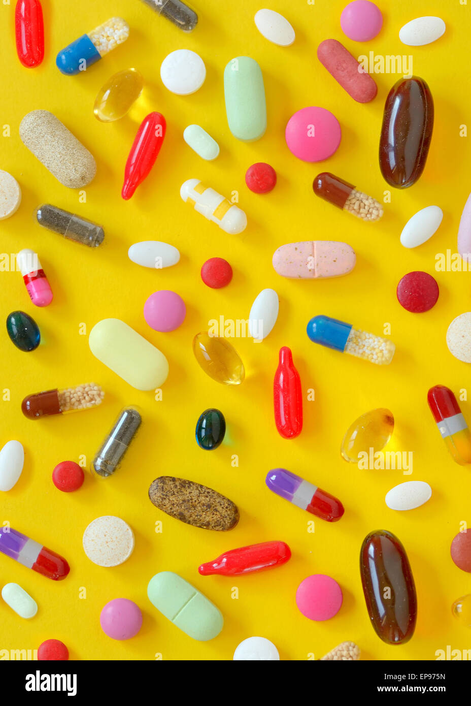 many different pills on yellow background Stock Photo - Alamy