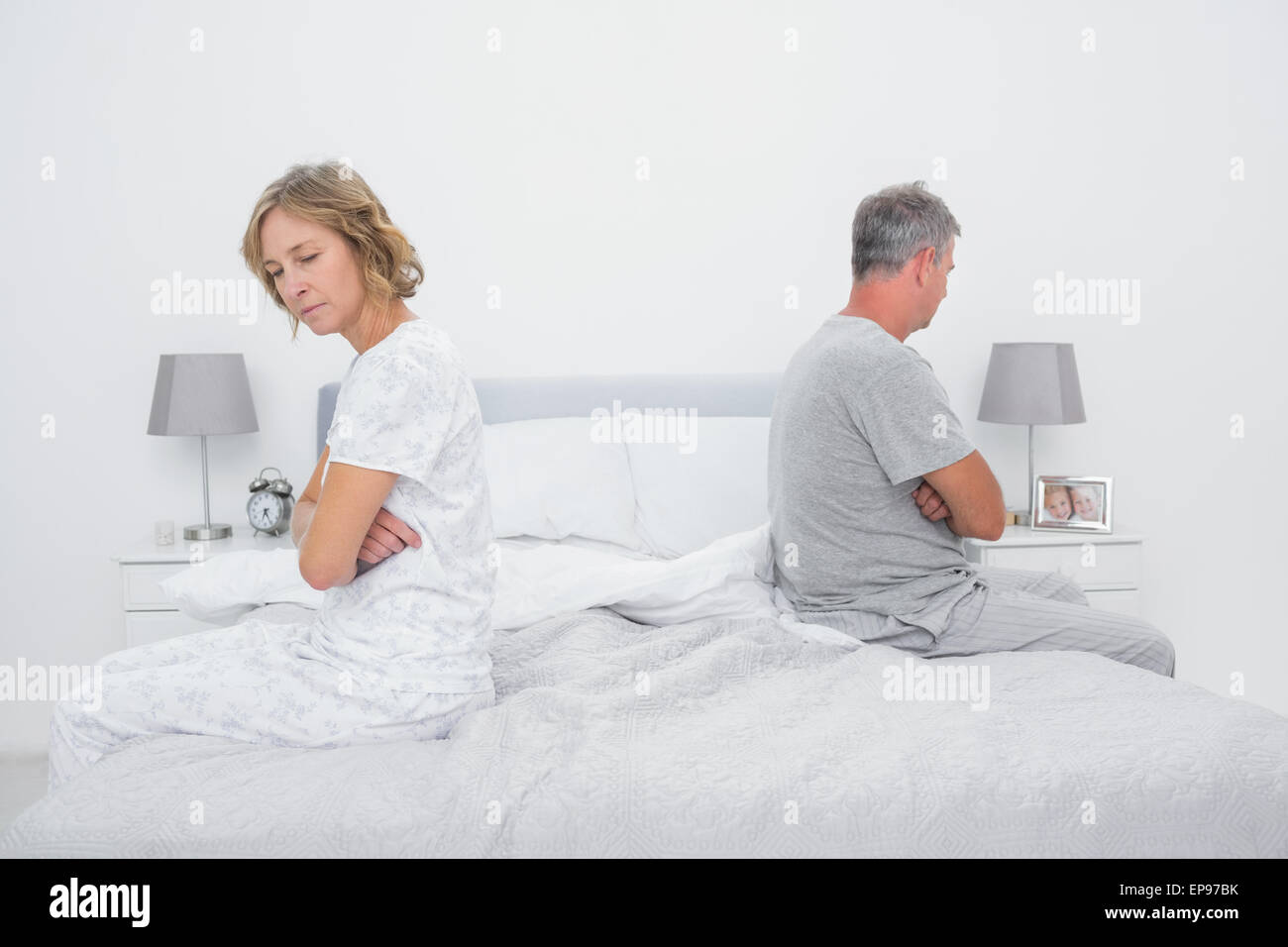 Couple Sitting On Different Sides Of Bed Not Talking After Fight Stock