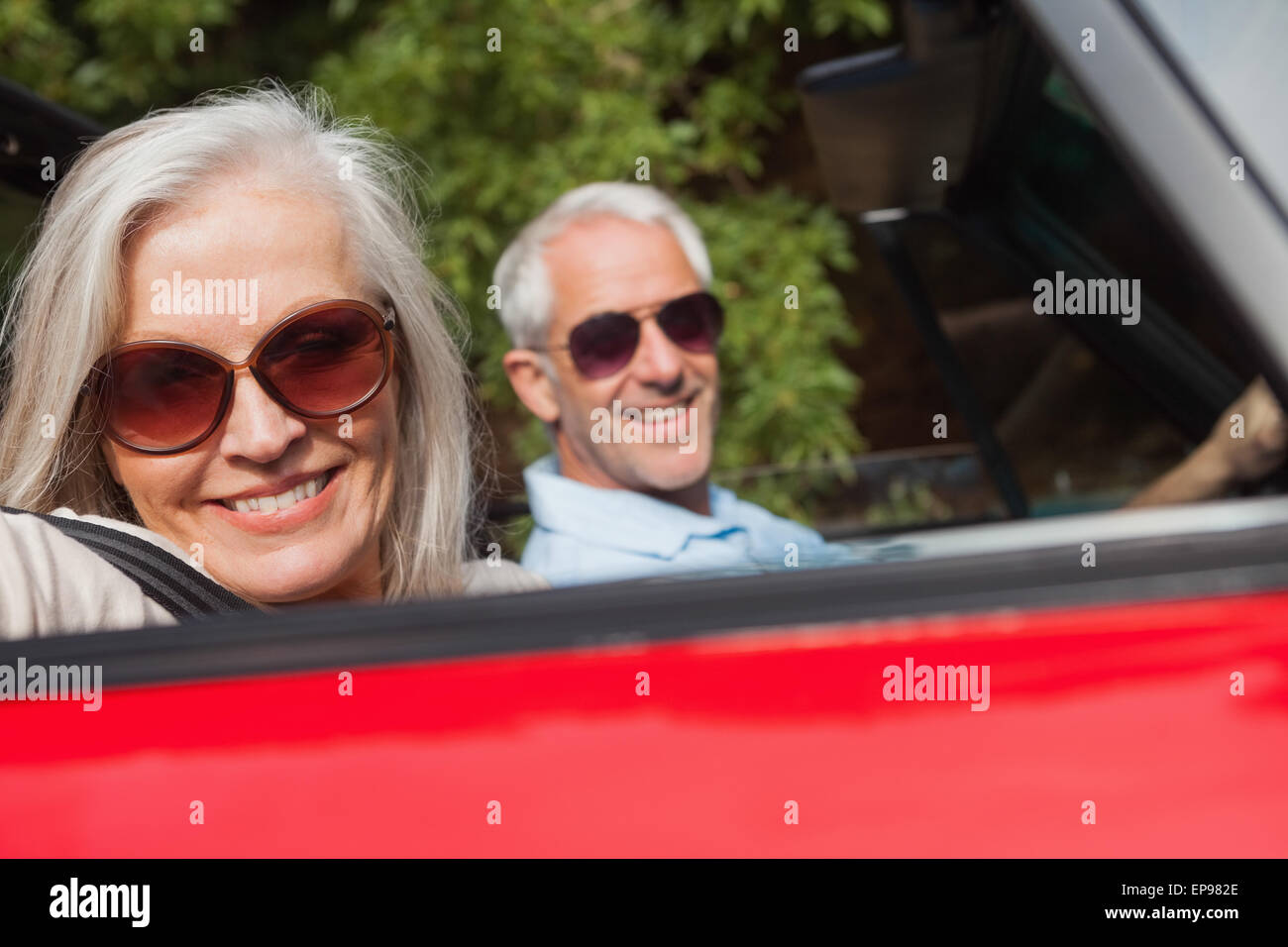 Side view of cheerful mature couple driving red cabriolet Stock Photo ...