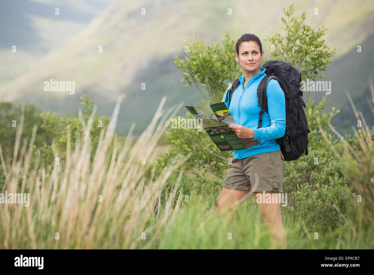Attractive female hiker with backpack holding a map Stock Photo - Alamy