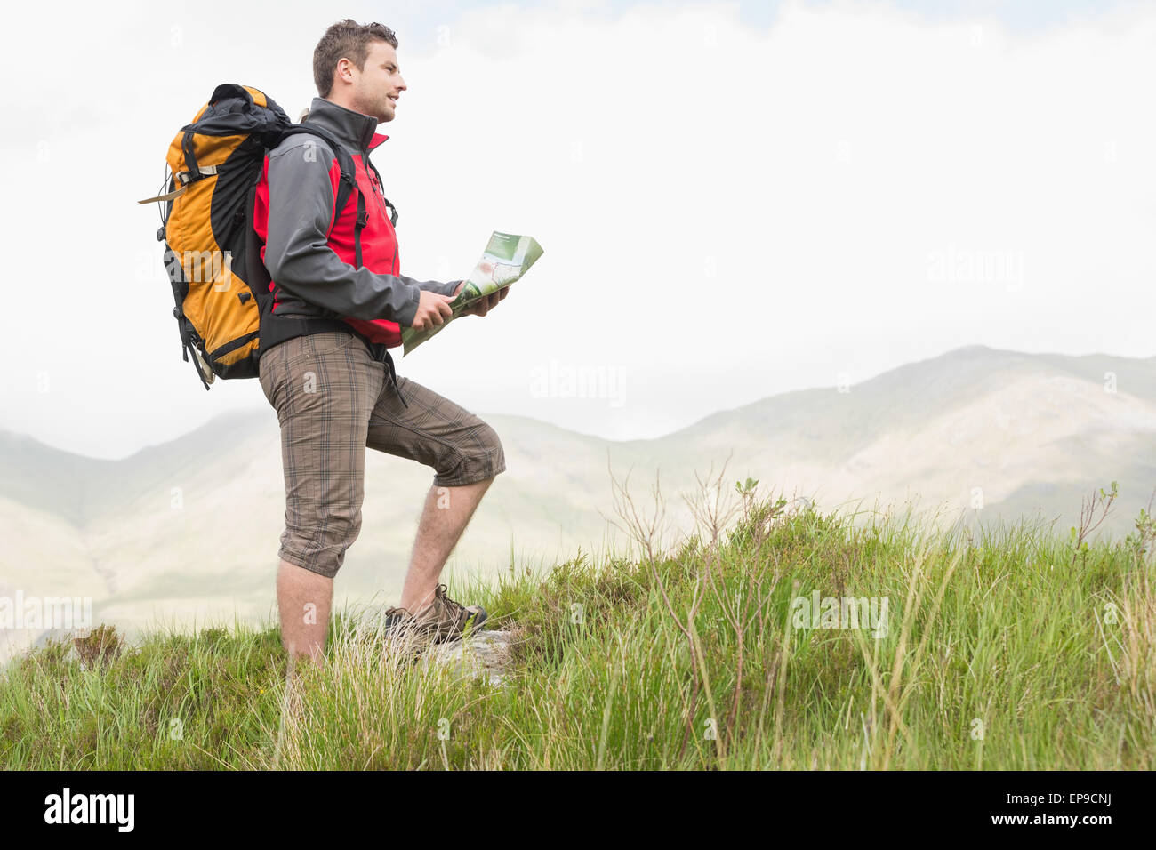 Handsome hiker with backpack hiking uphill holding a map Stock Photo ...