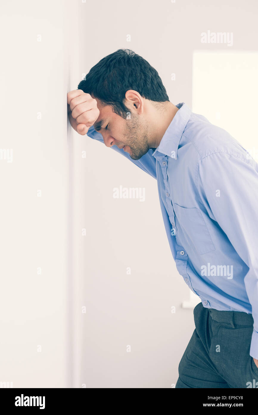 Devastated man leaning his head against a wall Stock Photo - Alamy