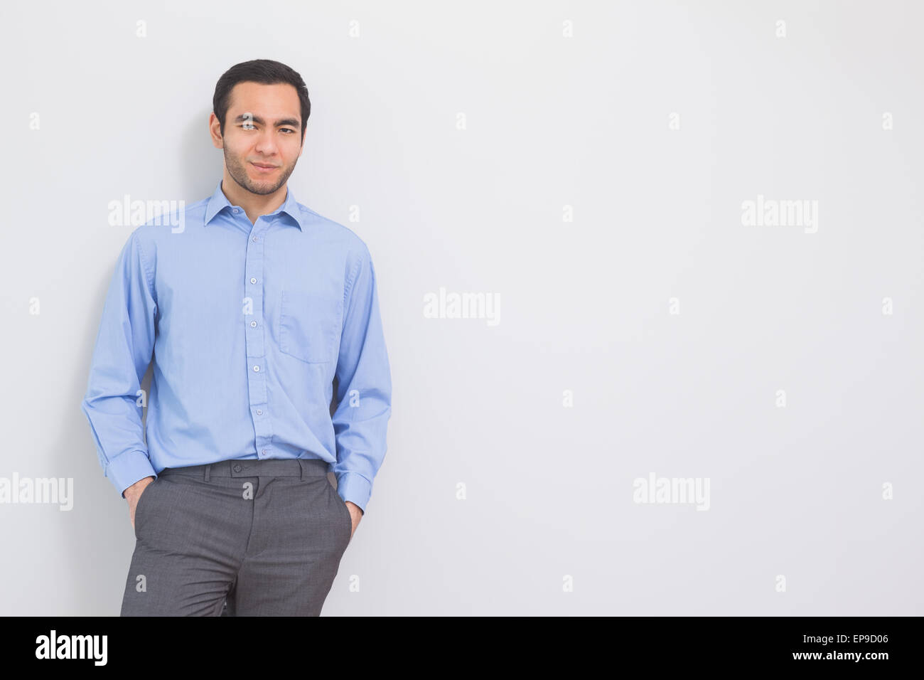 Content man leaning against a wall hands in the pockets Stock Photo - Alamy