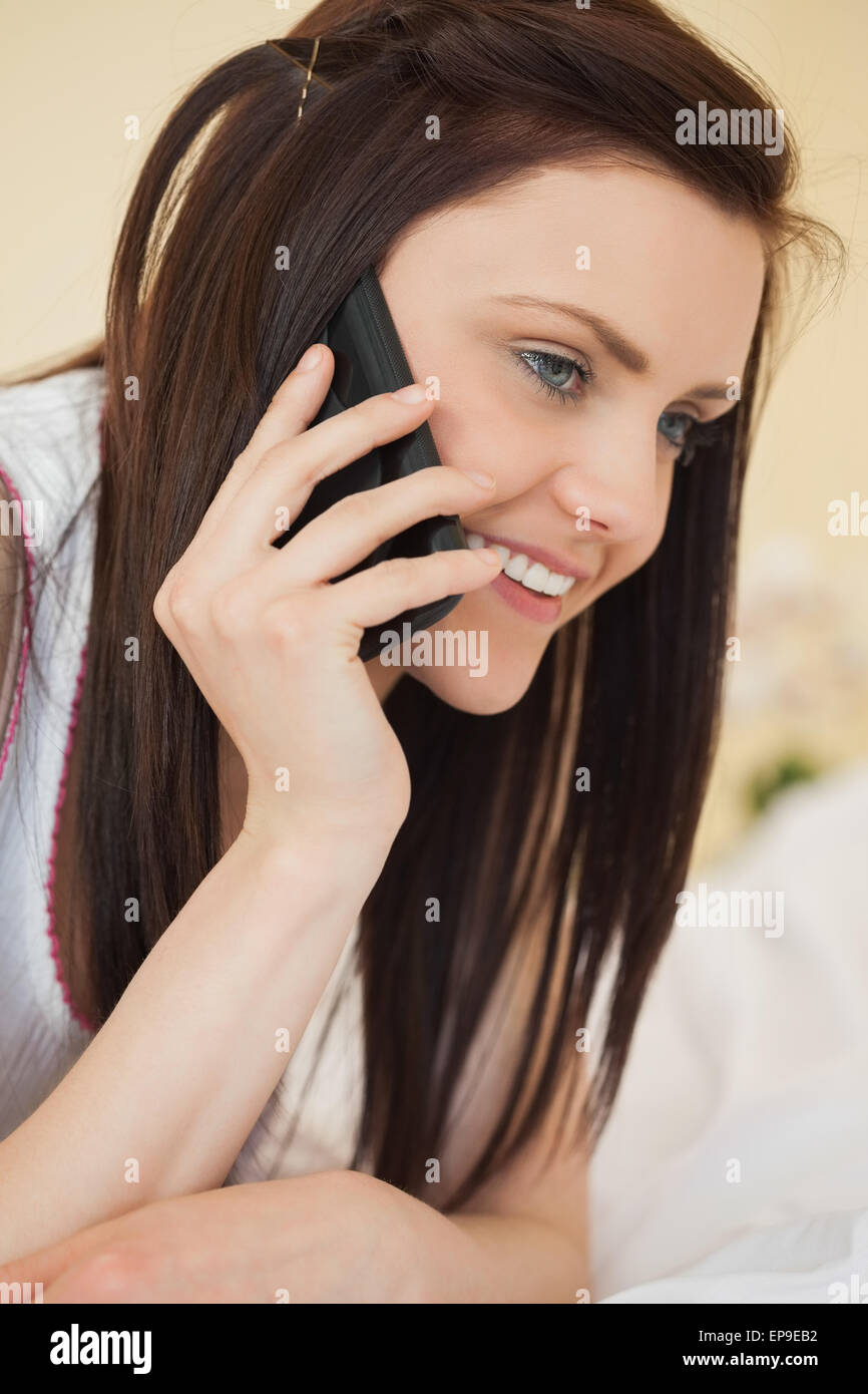 Smiling girl calling someone with a mobile phone lying on a bed Stock ...