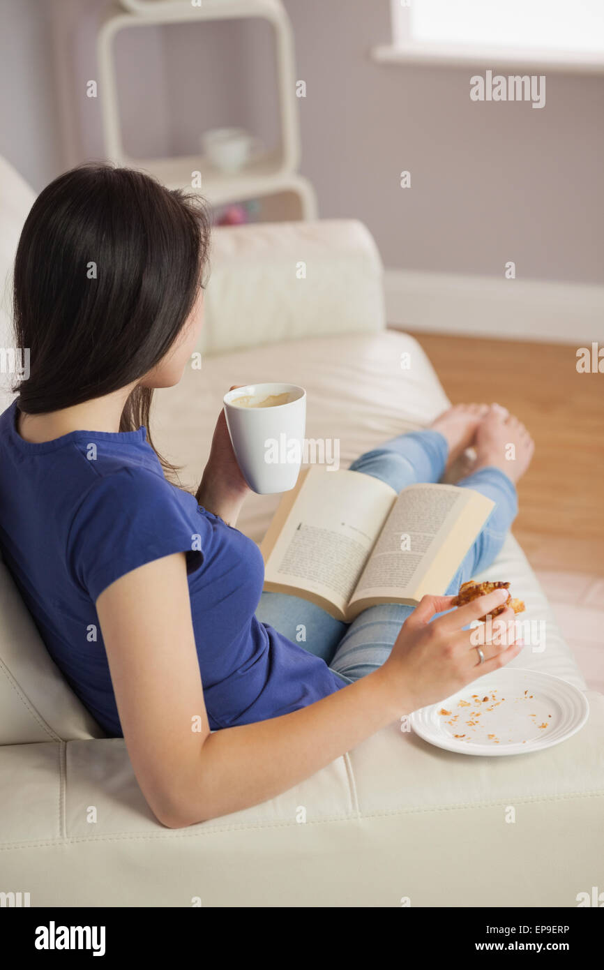 Young woman reading a book and eating pastry with coffee Stock Photo ...