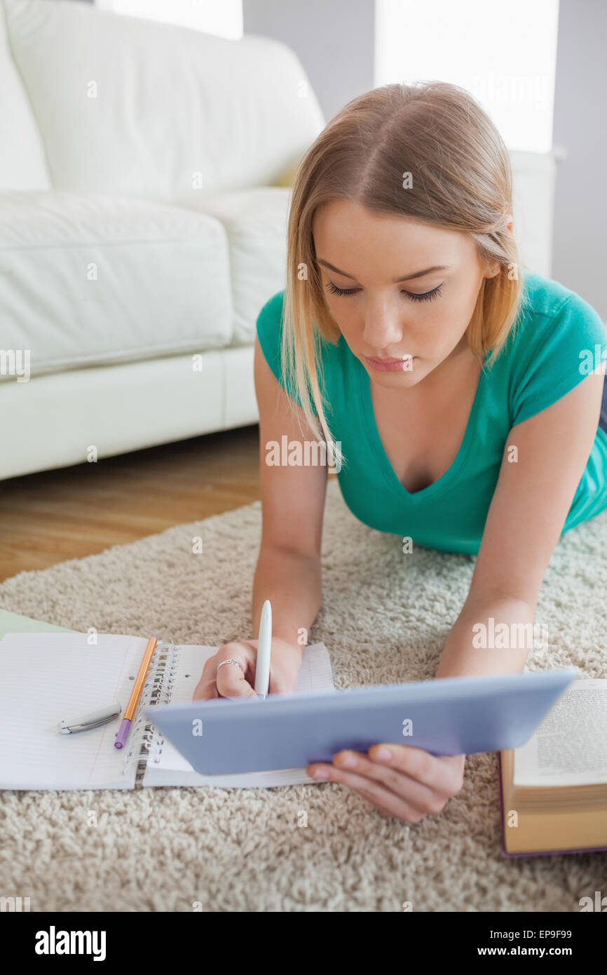 Attractive woman lying on floor using tablet to do her assignment Stock ...