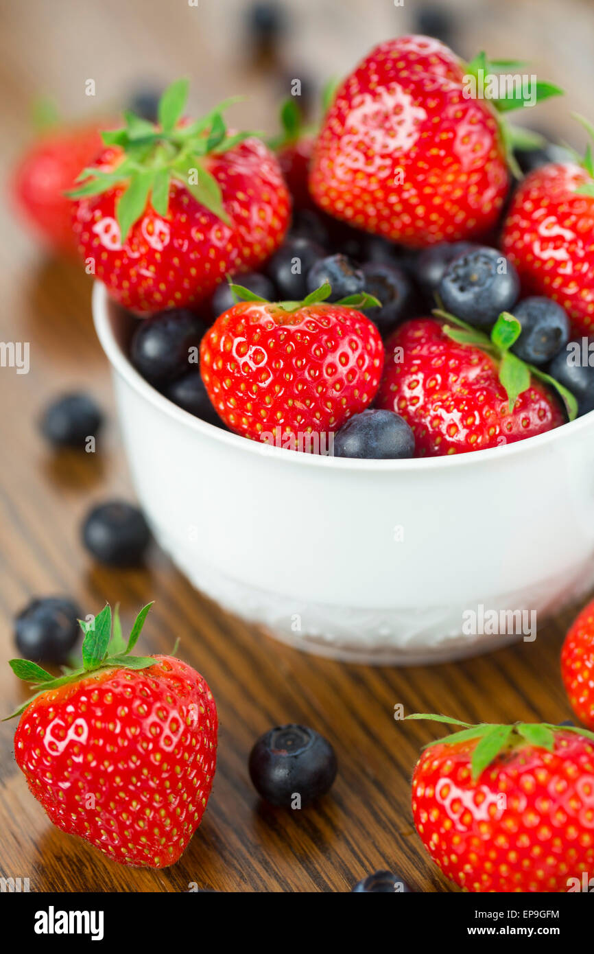 Bowl of strawberries and blueberries on a wooden table Stock Photo - Alamy