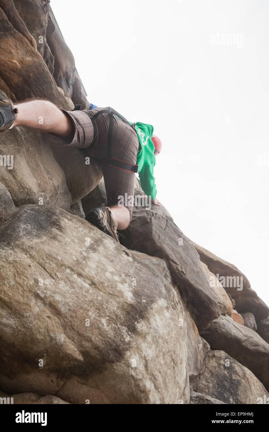 Determined man climbing a large rock face and seeing the summit Stock ...