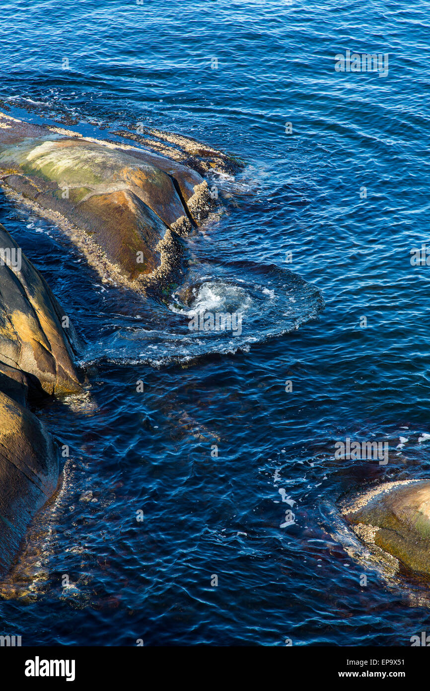 Granite rocks in the sea with swirling currents Stock Photo - Alamy