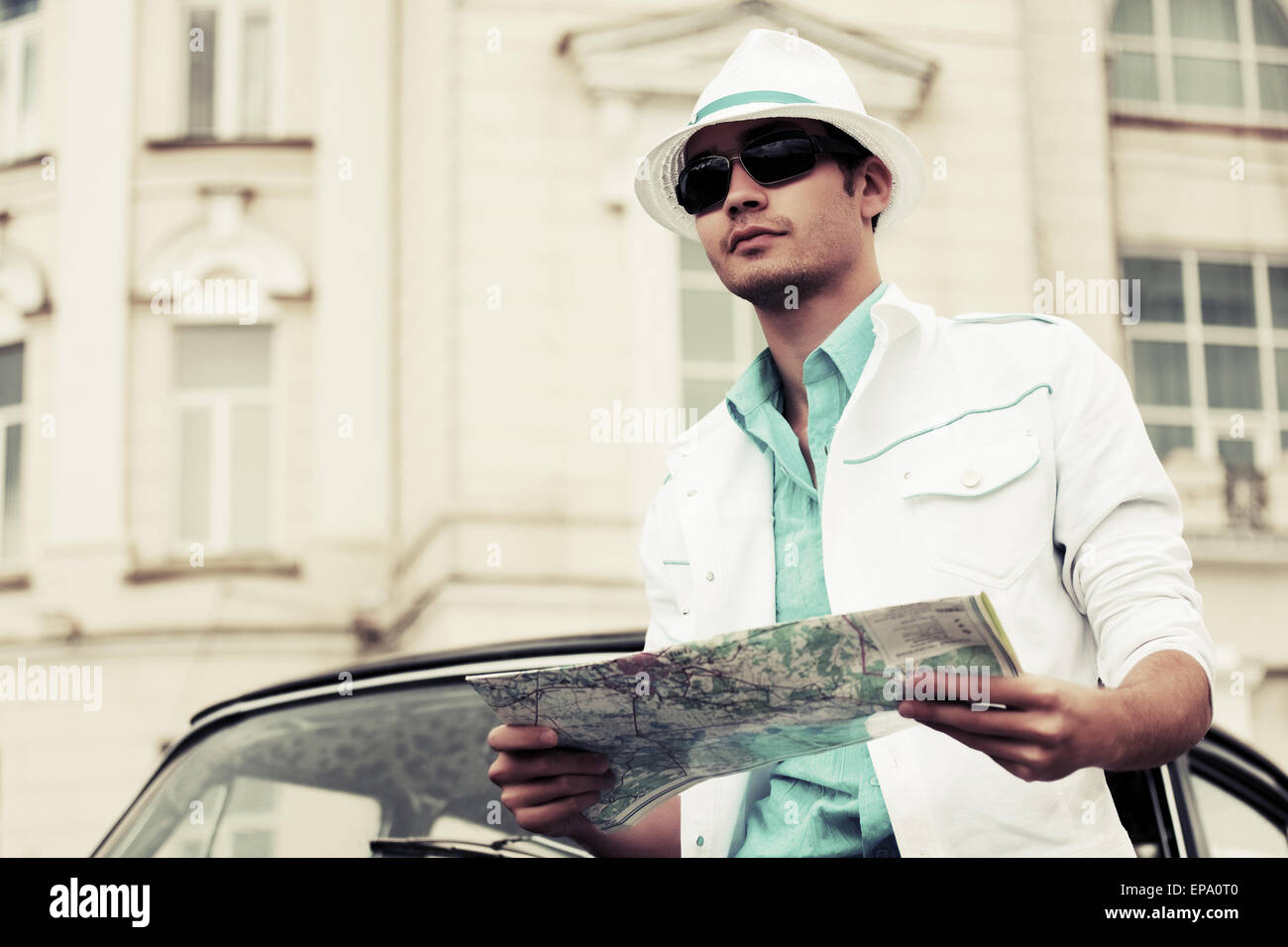 Young man holding a road map at the retro car Stock Photo - Alamy