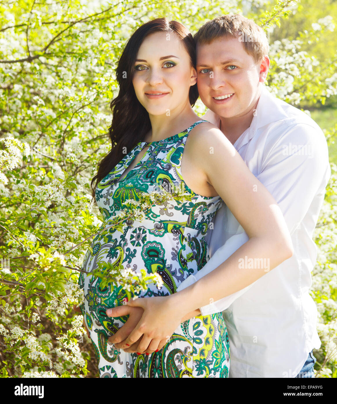 Young happy pregnant couple in the flowering spring park Stock Photo ...