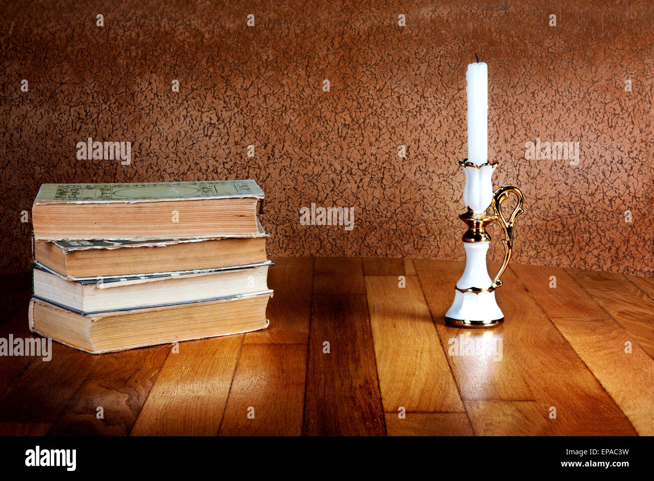 Old stack of books with candlestick and burning candle on the wooden ...