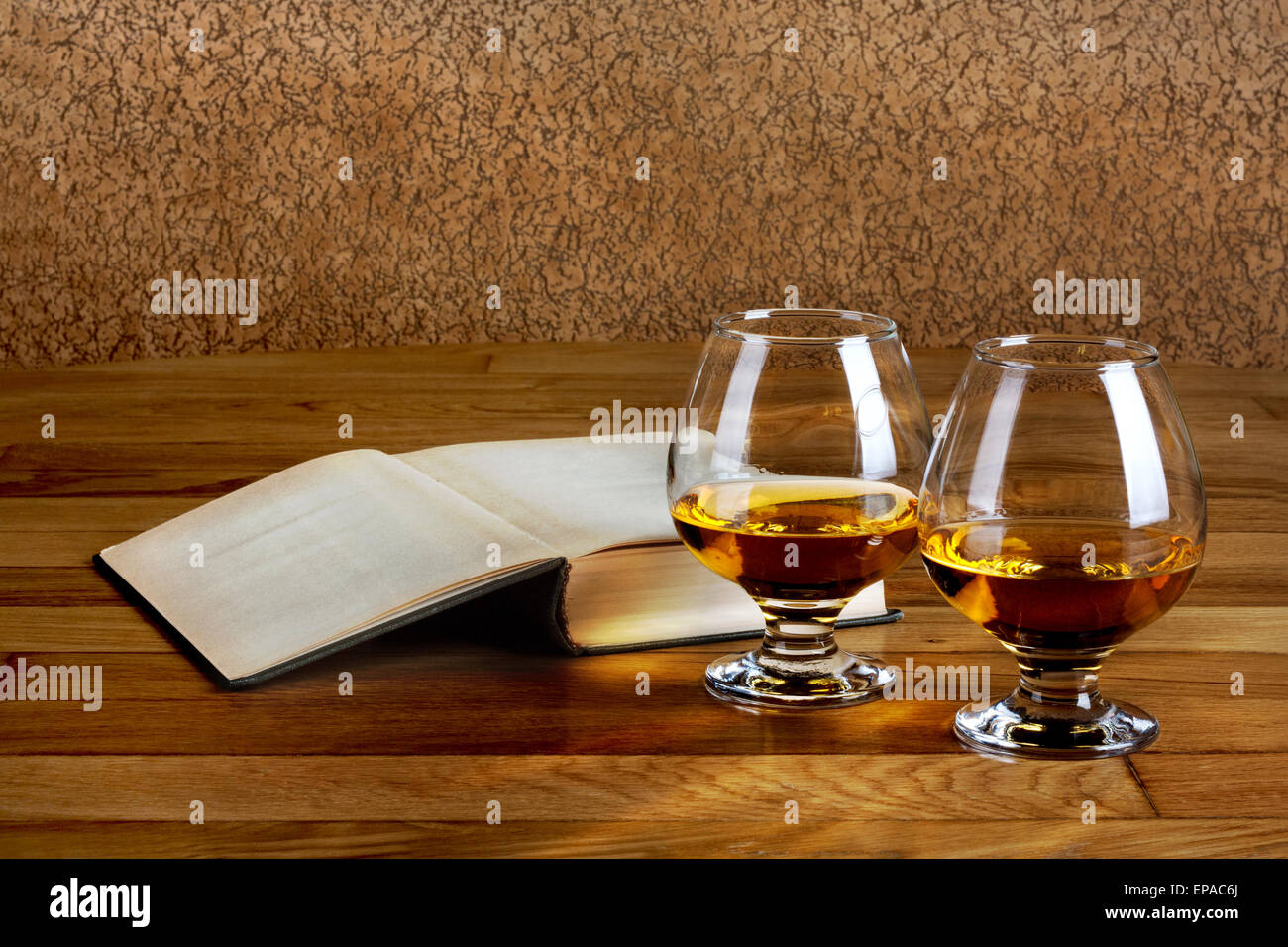 Two goblets of brandy and open book on wooden old counter top Stock ...