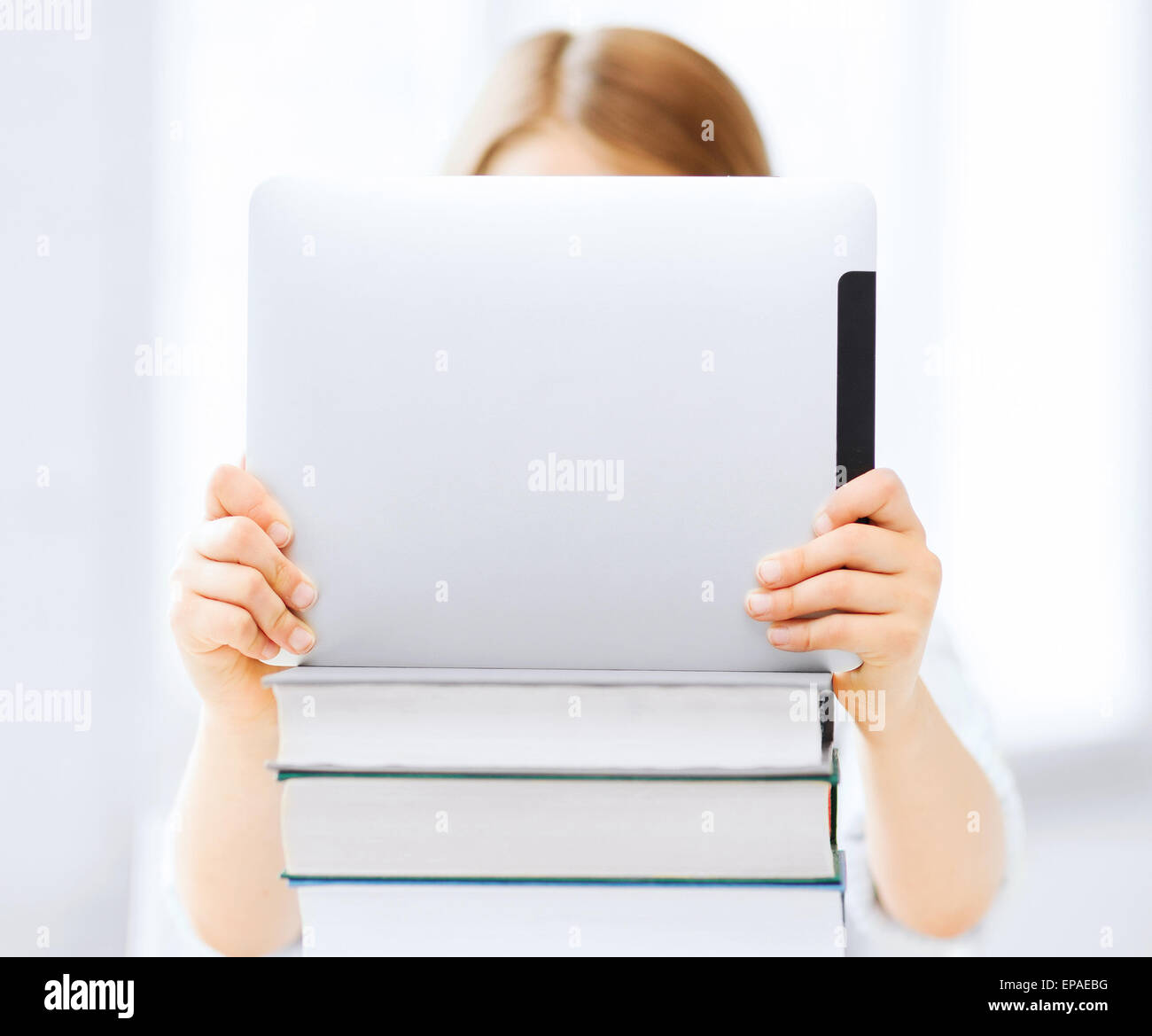 girl hiding behind tablet pc and books at school Stock Photo - Alamy