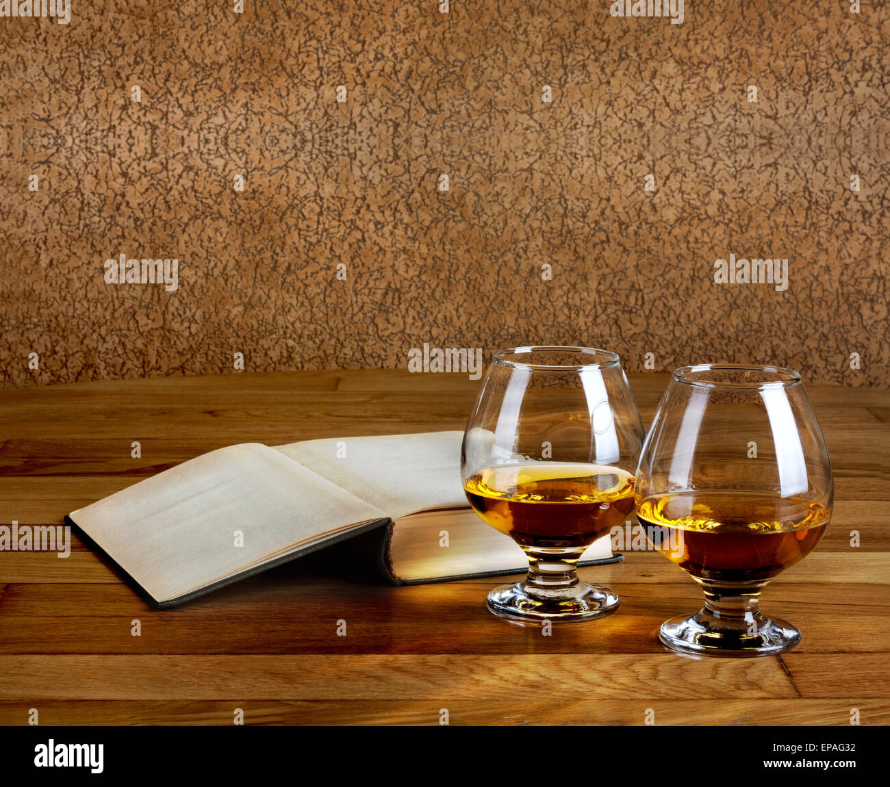 Two goblets of brandy and open book on wooden old counter top Stock ...