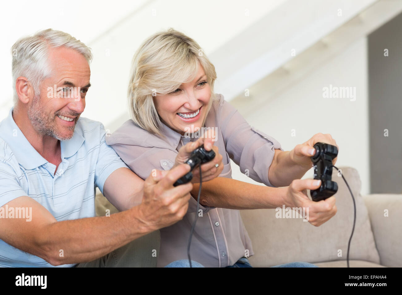Cheerful mature couple playing video game on sofa Stock Photo - Alamy