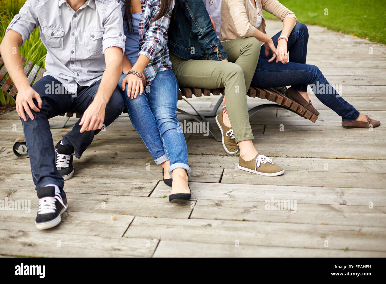 close up of many legs sitting on bench at park Stock Photo - Alamy